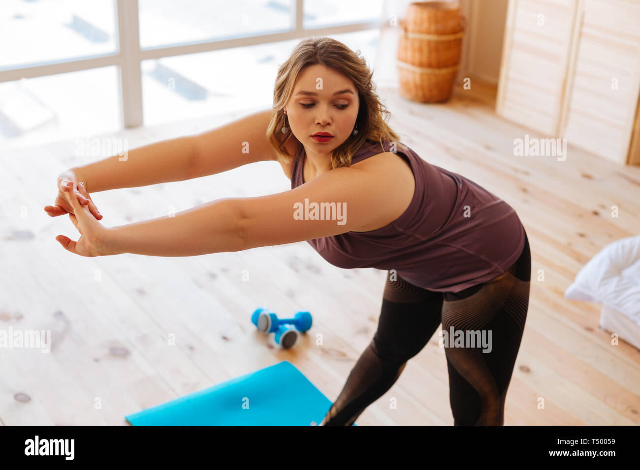 Special exercise. Pretty young woman leaning her body forward while ...