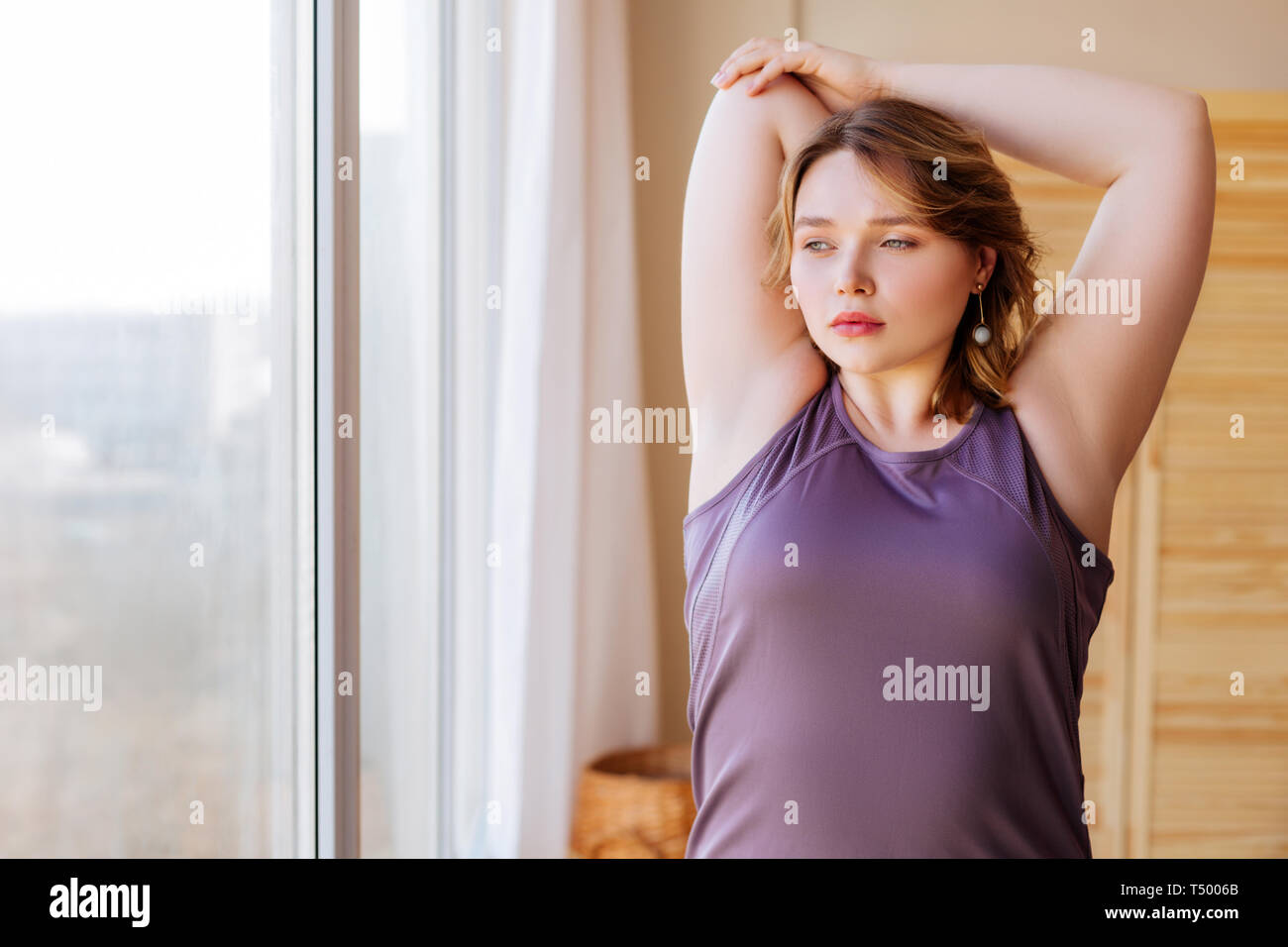 Special pose. Pretty nice woman touching her back while stretching her body Stock Photo - Alamy