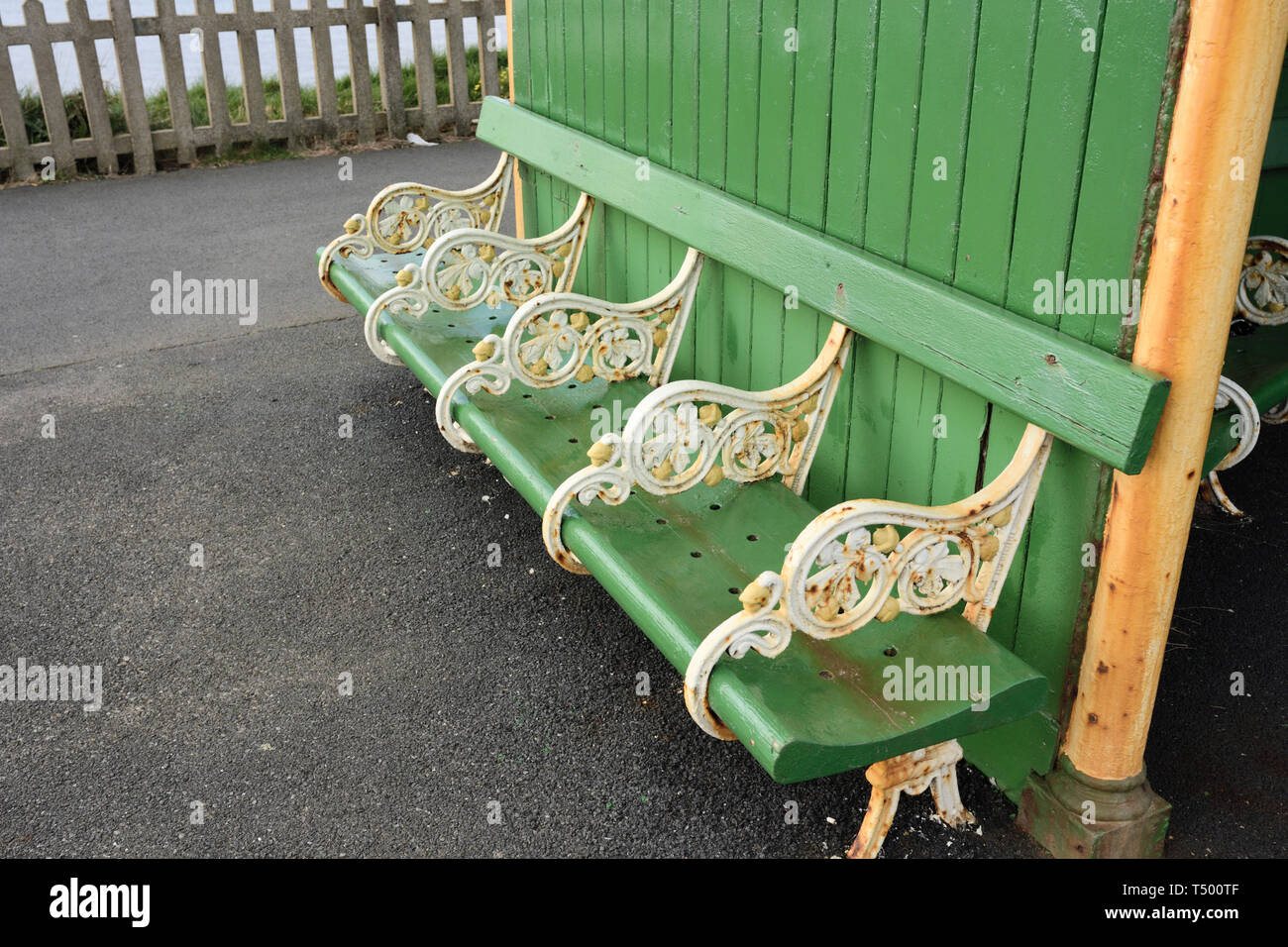 Cast iron frame bench with green wooden seat and backrest on outside of ...