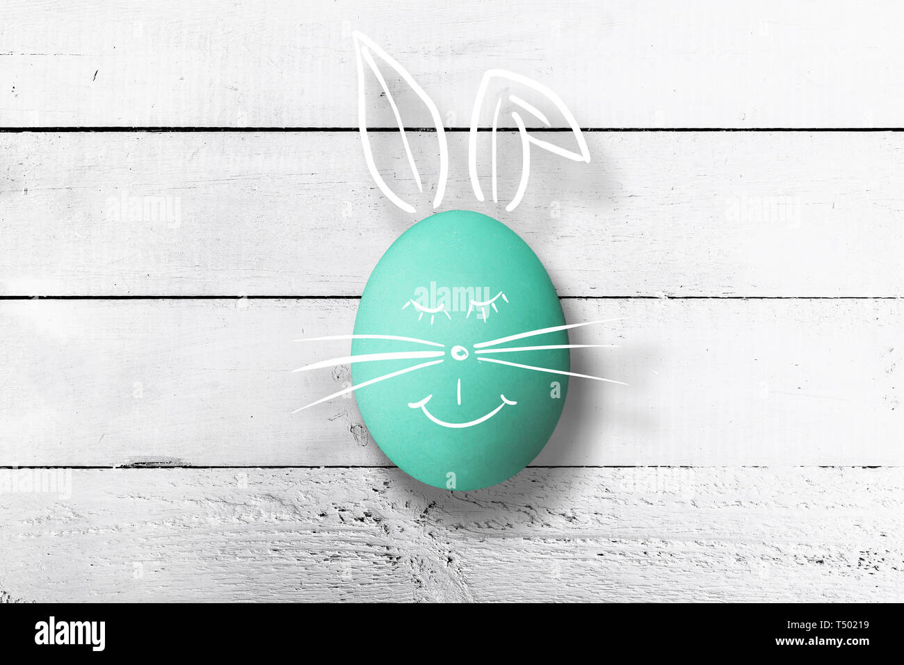 easter bunny face drawn on easter egg against white rustic wooden table ...
