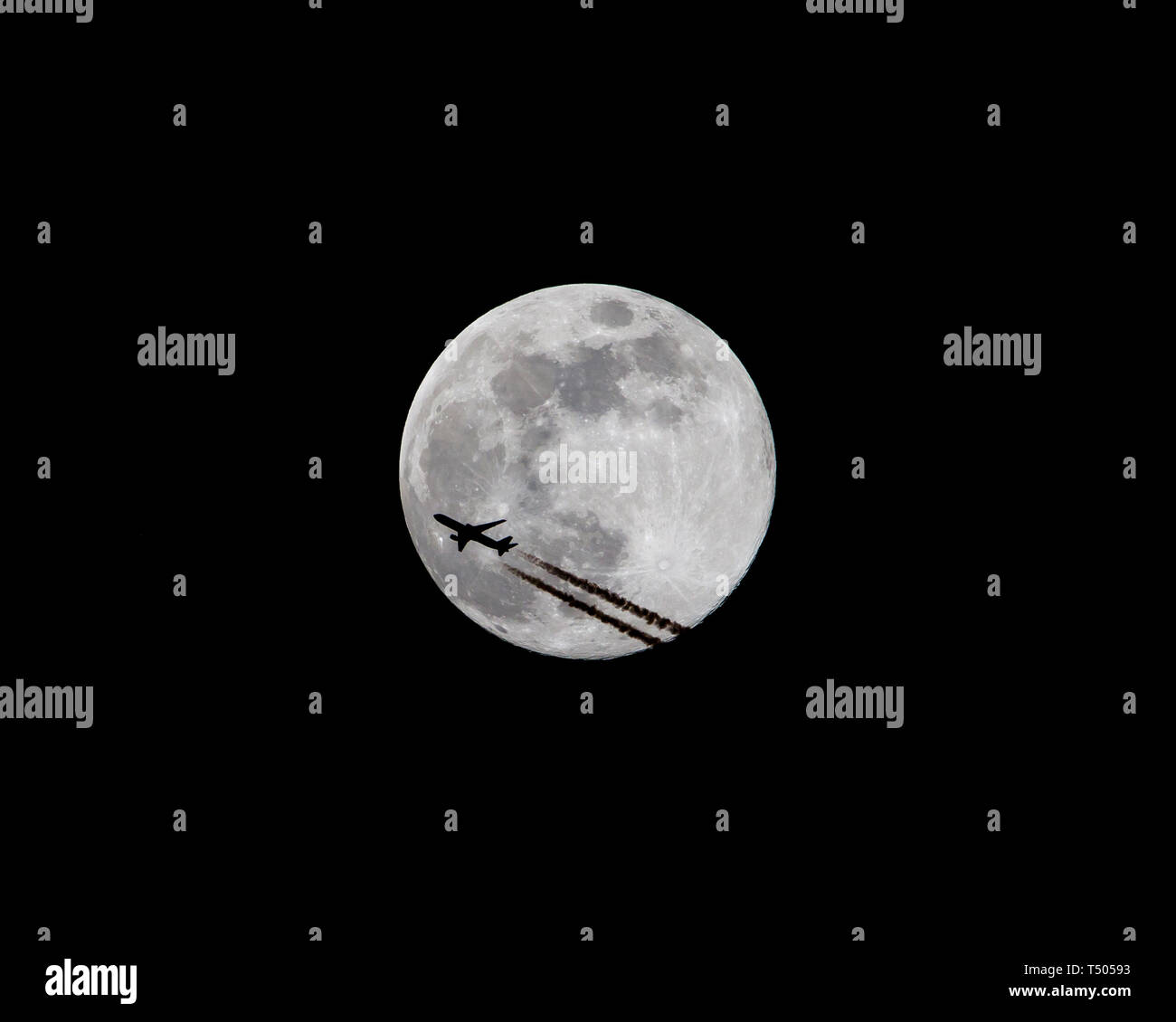 A commercial airliner at high altitude is silhouetted as it passes in ...