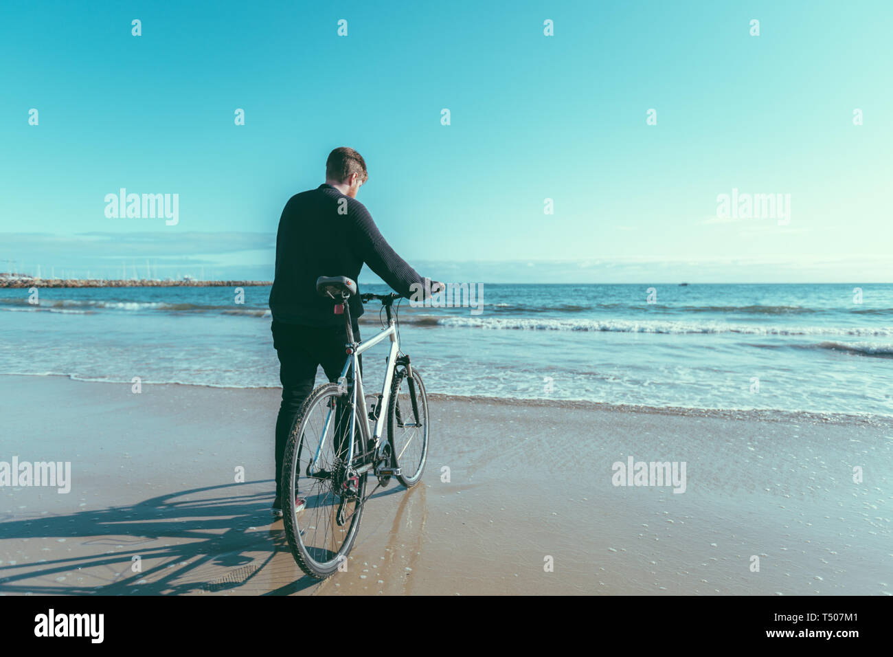 Man riding bike on beach Stock Photo - Alamy