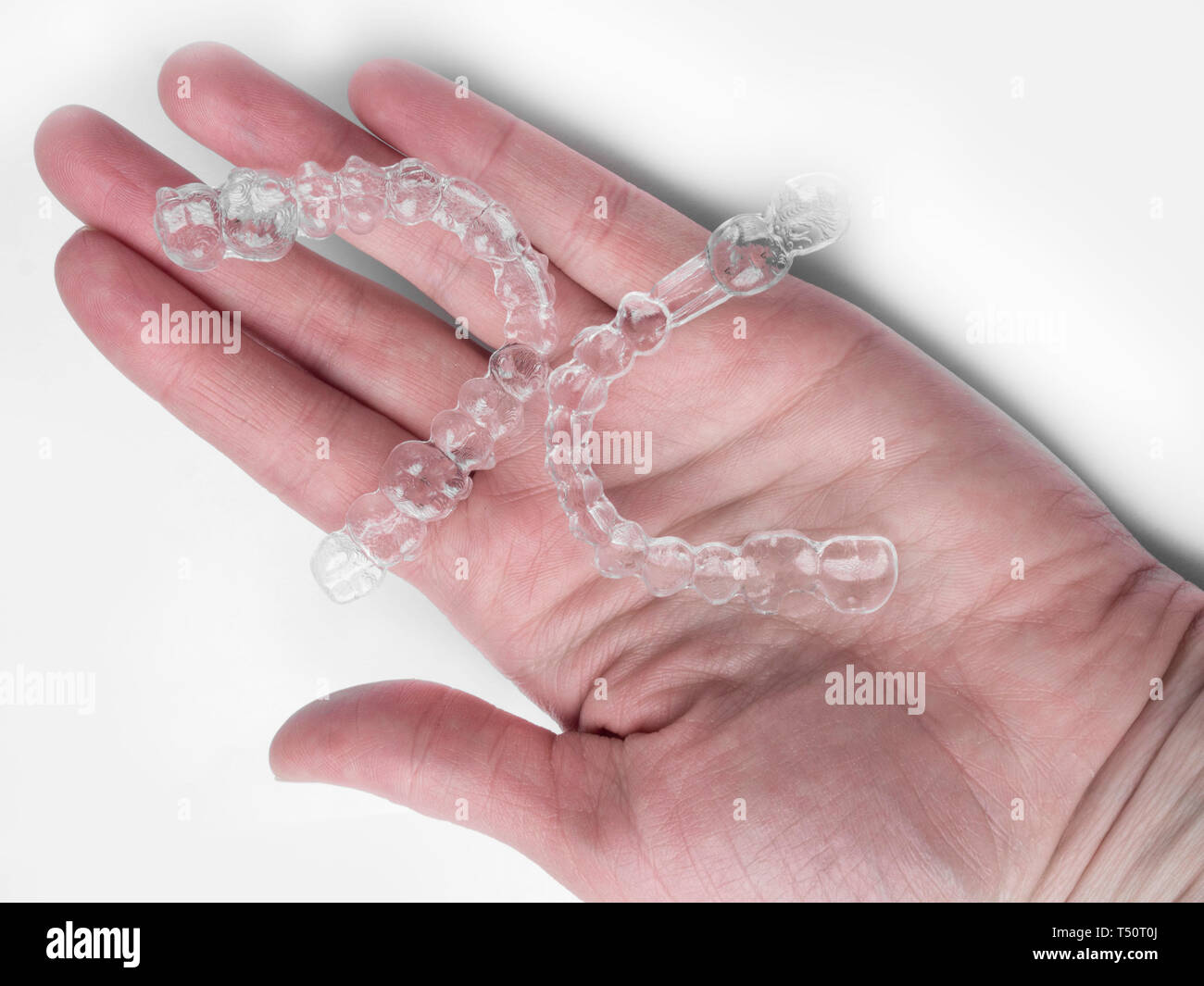 Ready to adjust my teeth. Hand is holding transparent orthodontic ...