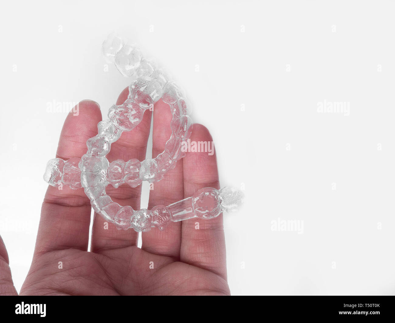 Ready to adjust my teeth. Hand is holding transparent orthodontic ...