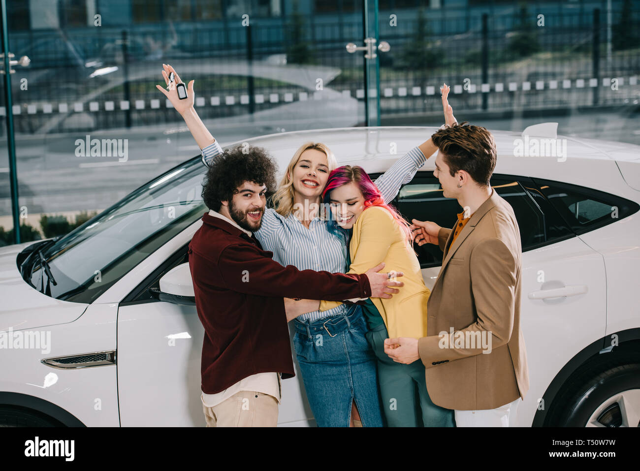 cheerful group of friends hugging with attractive blonde girl near ...