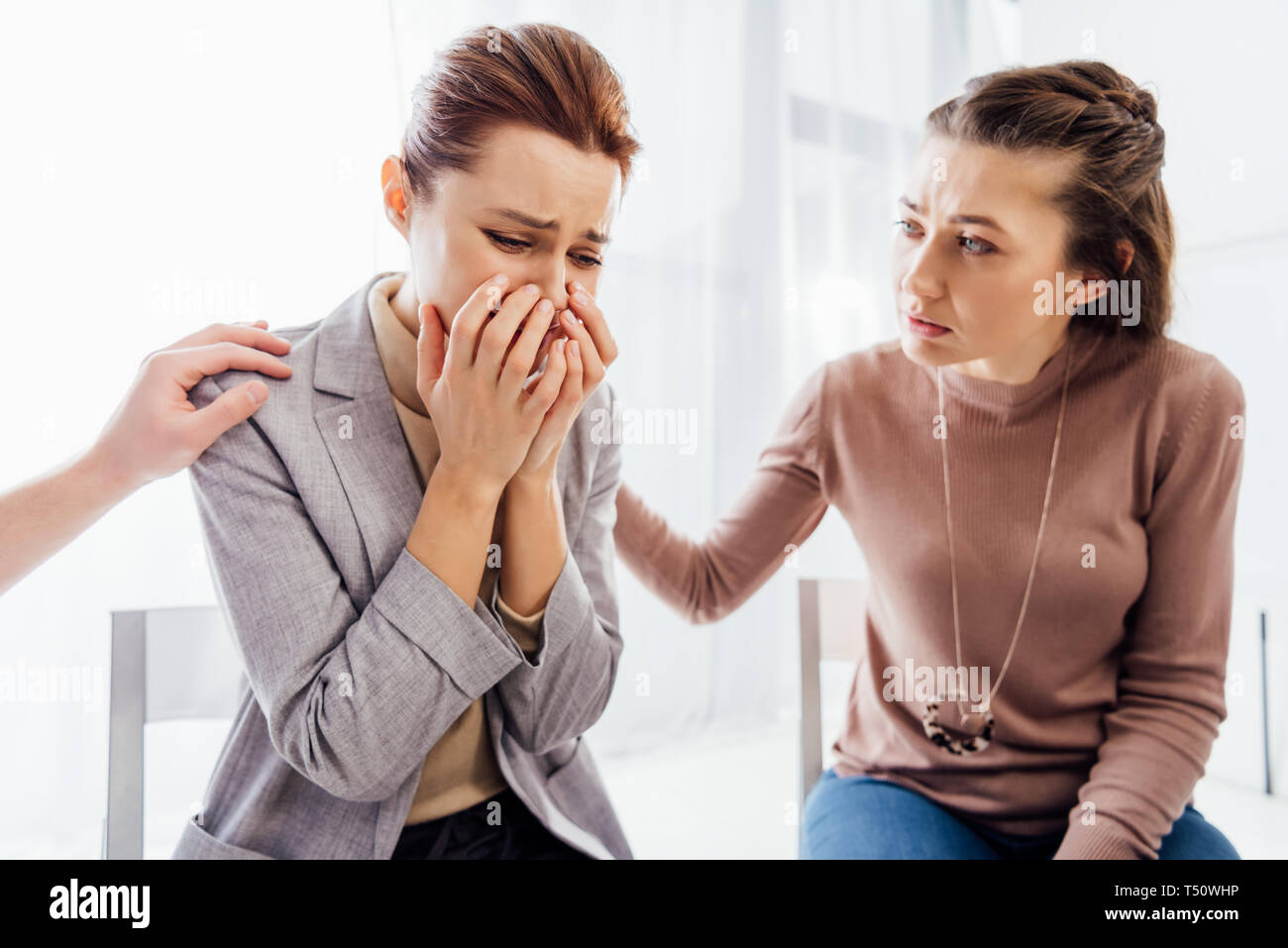 woman consoling another crying woman during therapy meeting Stock Photo ...