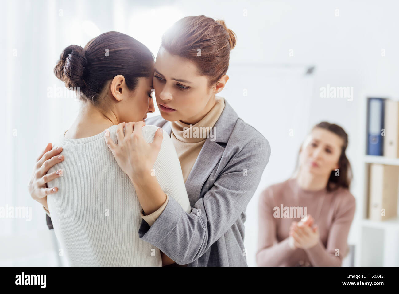 selective focus of woman embracing another woman during therapy meeting ...