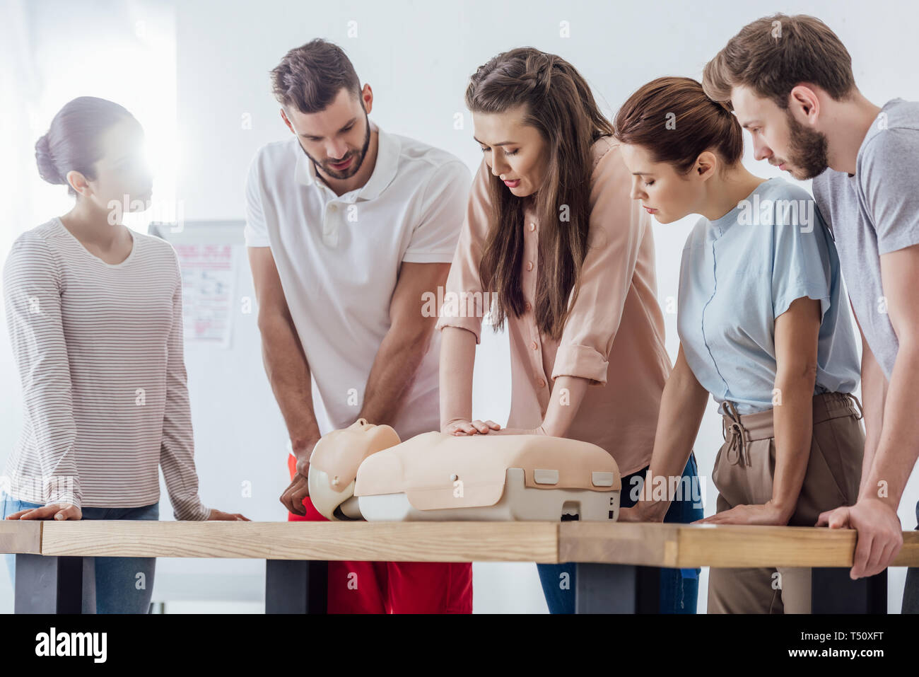group of concentrated people performing cpr on dummy during first aid ...