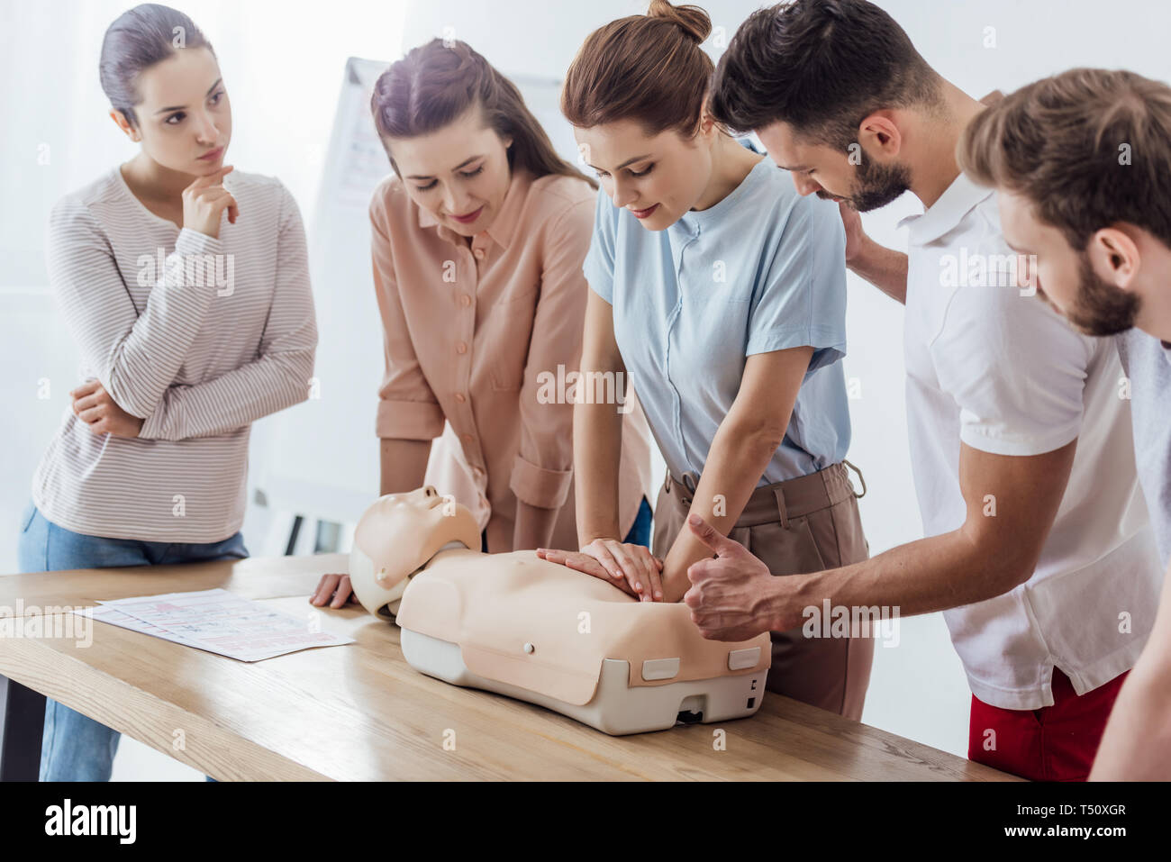 group of focused people performing cpr on dummy during first aid ...