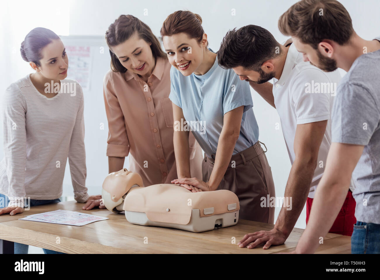 beautiful smiling woman looking at camera while performing cpr on dummy ...