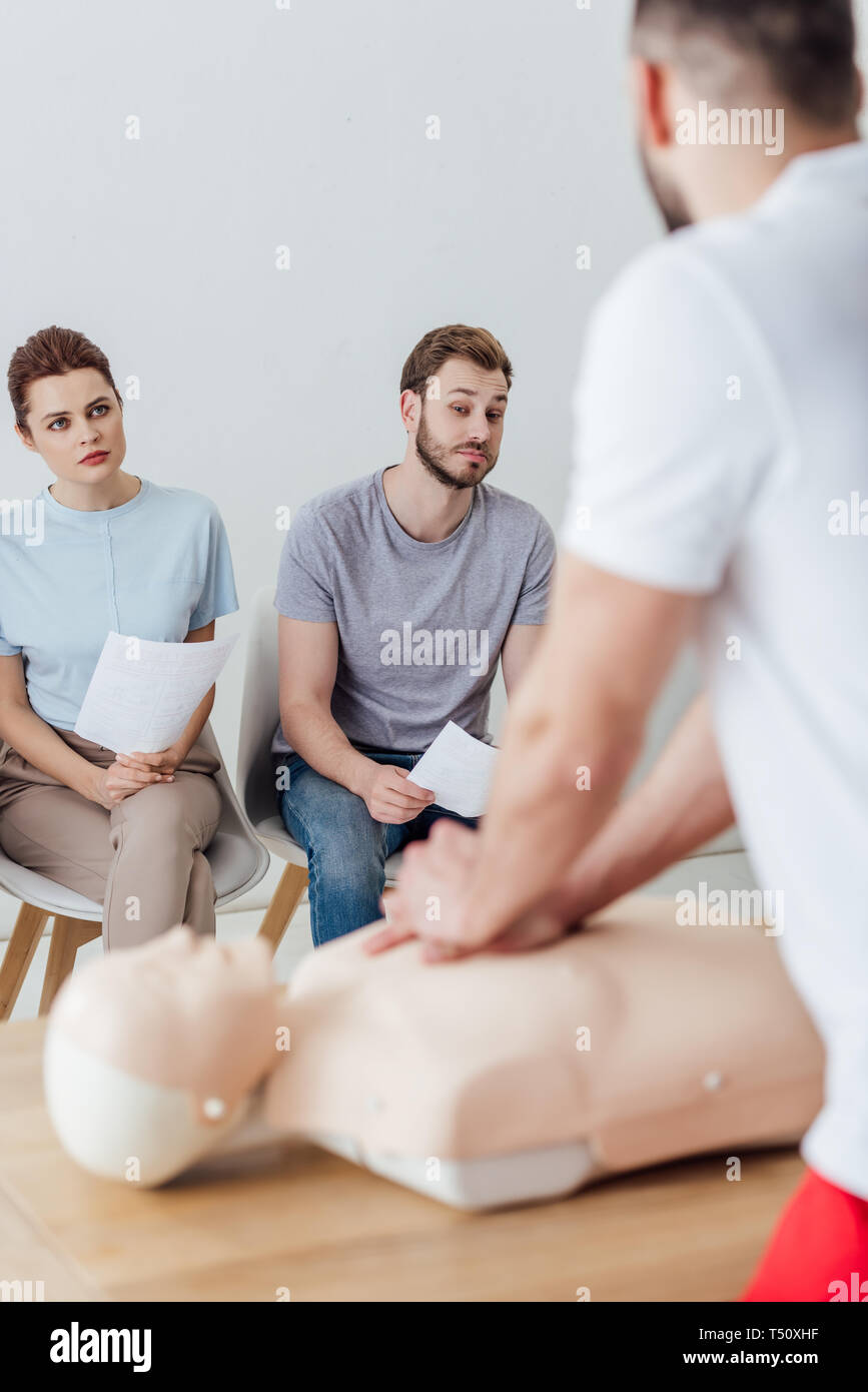 back view of instructor performing chest compression on dummy during ...