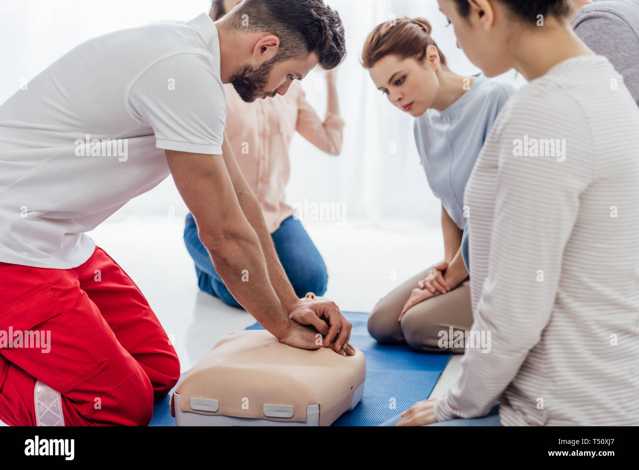 instructor performing cpr on dummy during first aid training with group ...