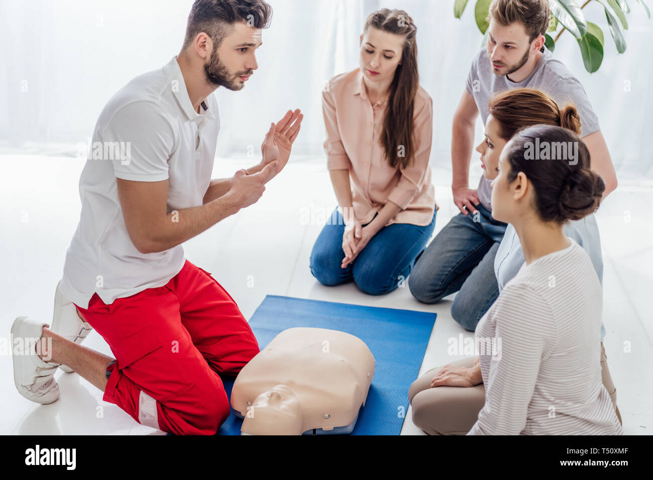handsome instructor gesturing during first aid training with group of ...