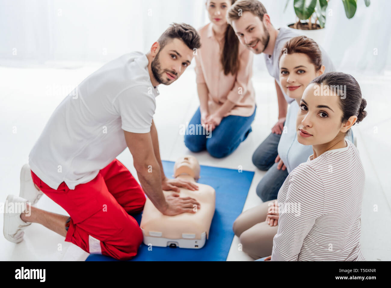 group of people with instructor looking at camera during first aid ...