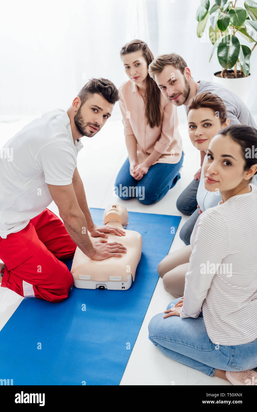 group of people with instructor looking at camera during first aid ...