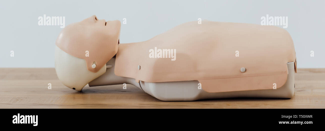 panoramic shot of cpr dummy for first aid training on wooden table ...