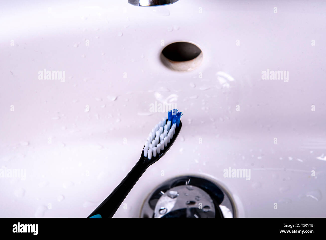 Toothbrush is cleaned in the sink under running water Stock Photo - Alamy