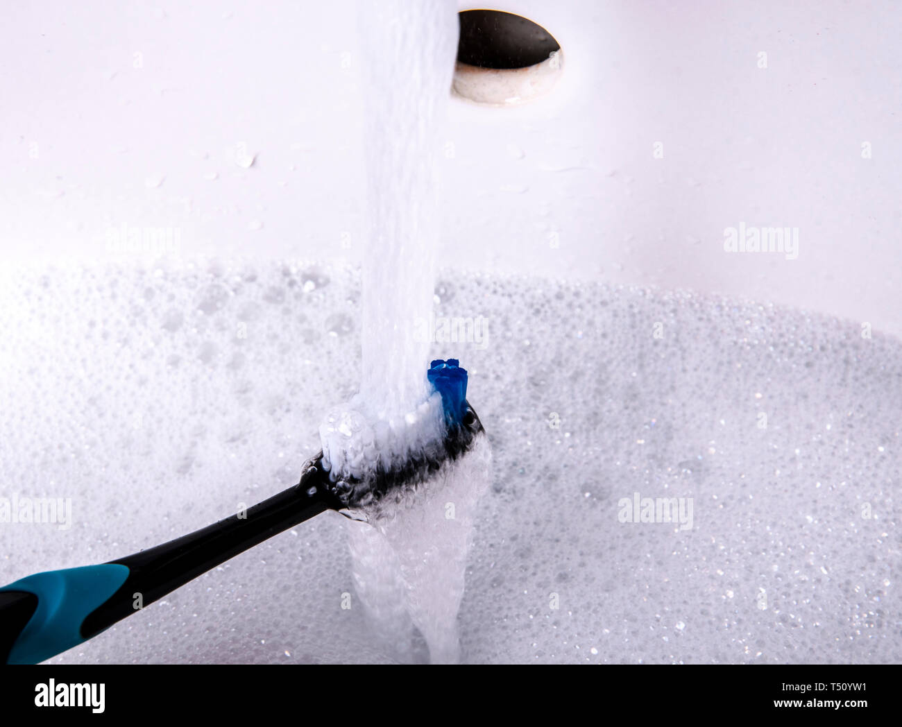 Toothbrush is cleaned in the sink under running water Stock Photo - Alamy