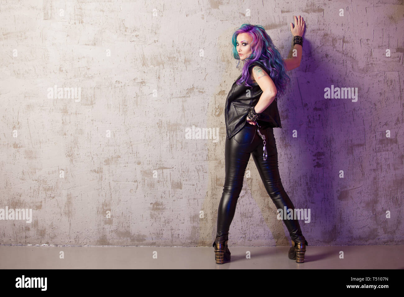 Daring rebel rocker, a portrait on a background of gray grunge wall ...