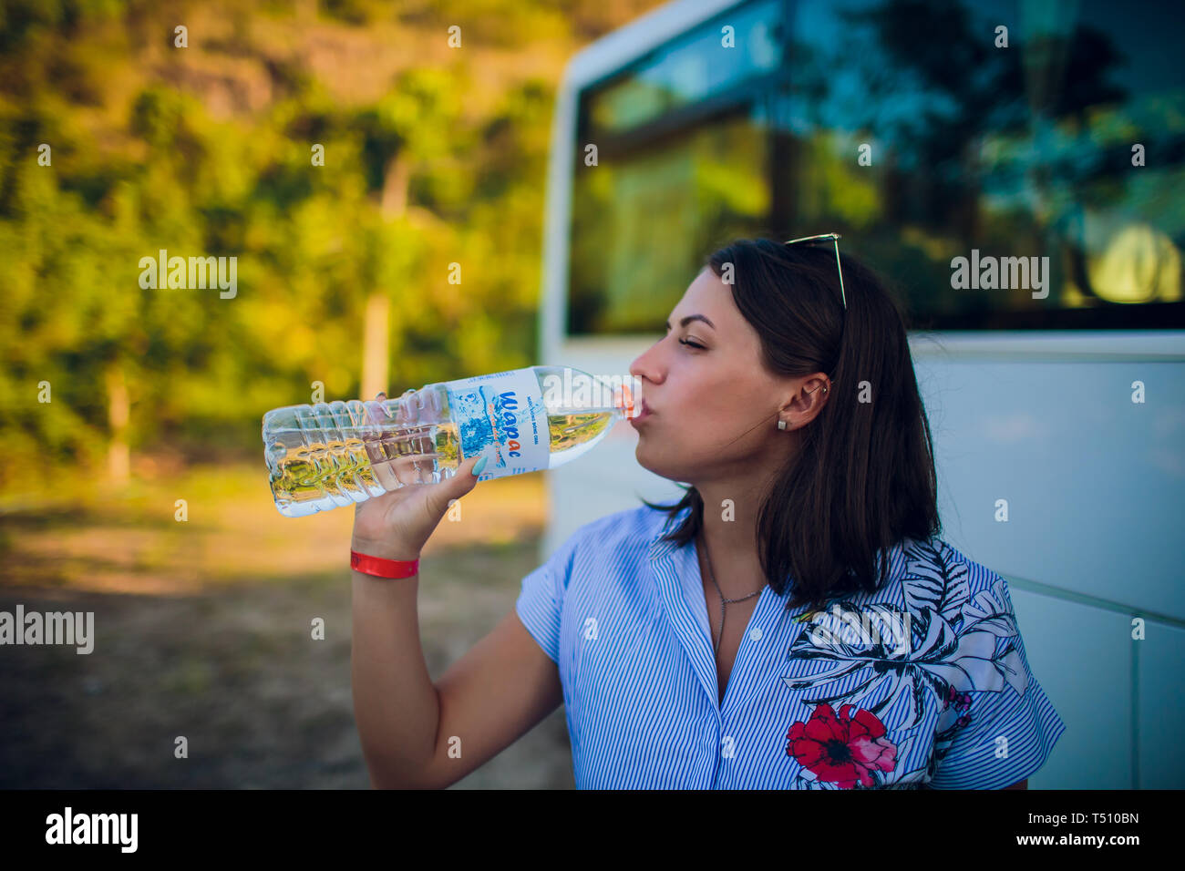 woman drinking water after running outdoors on the background of the ...