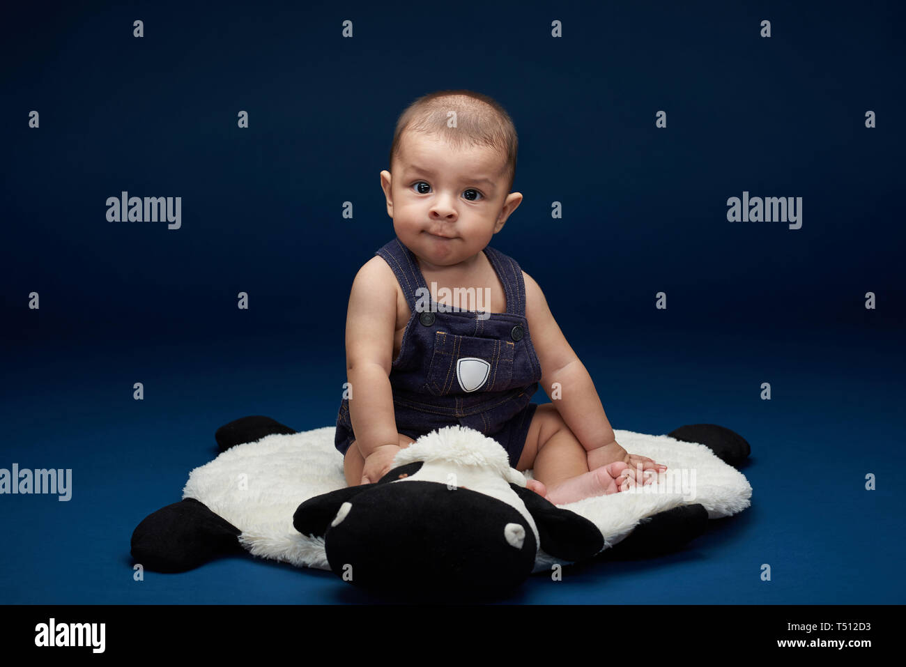 One baby boy sitting on blue studio background Stock Photo - Alamy