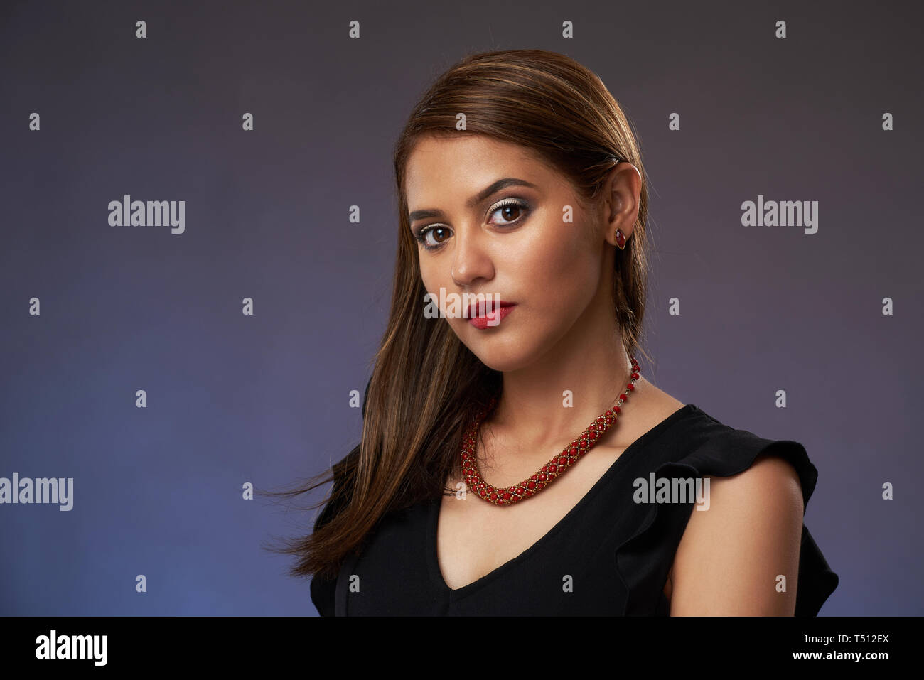 Seriously looking young woman on dark blue background Stock Photo - Alamy
