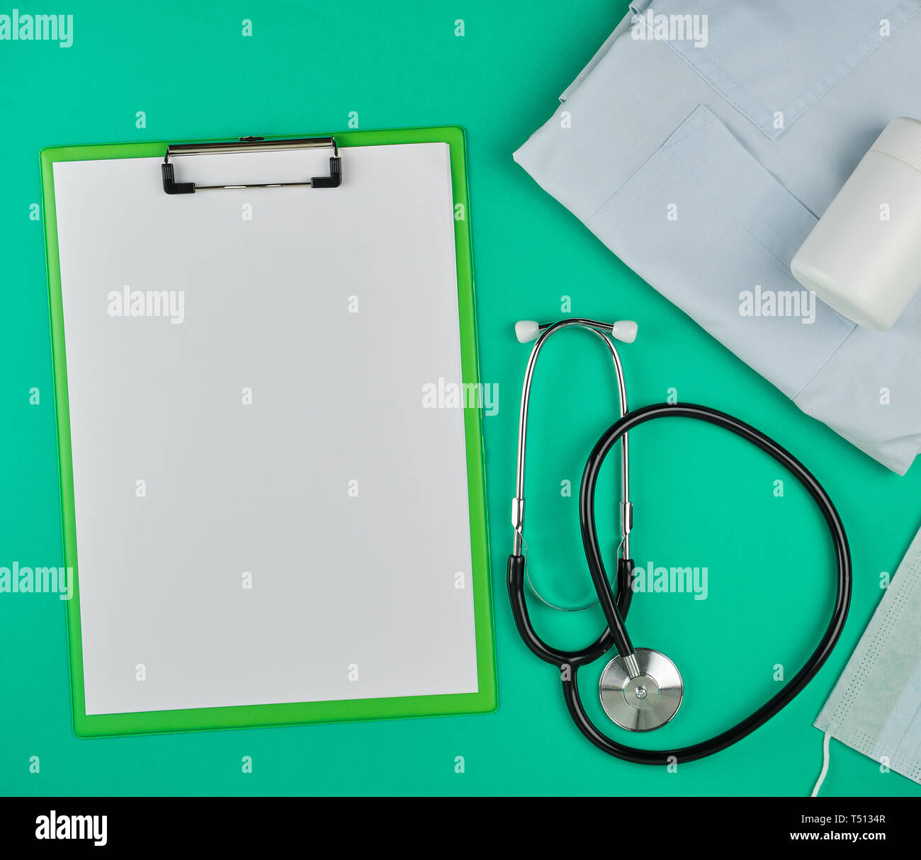 paper holder with empty white sheets, medical stethoscope, pills on a ...