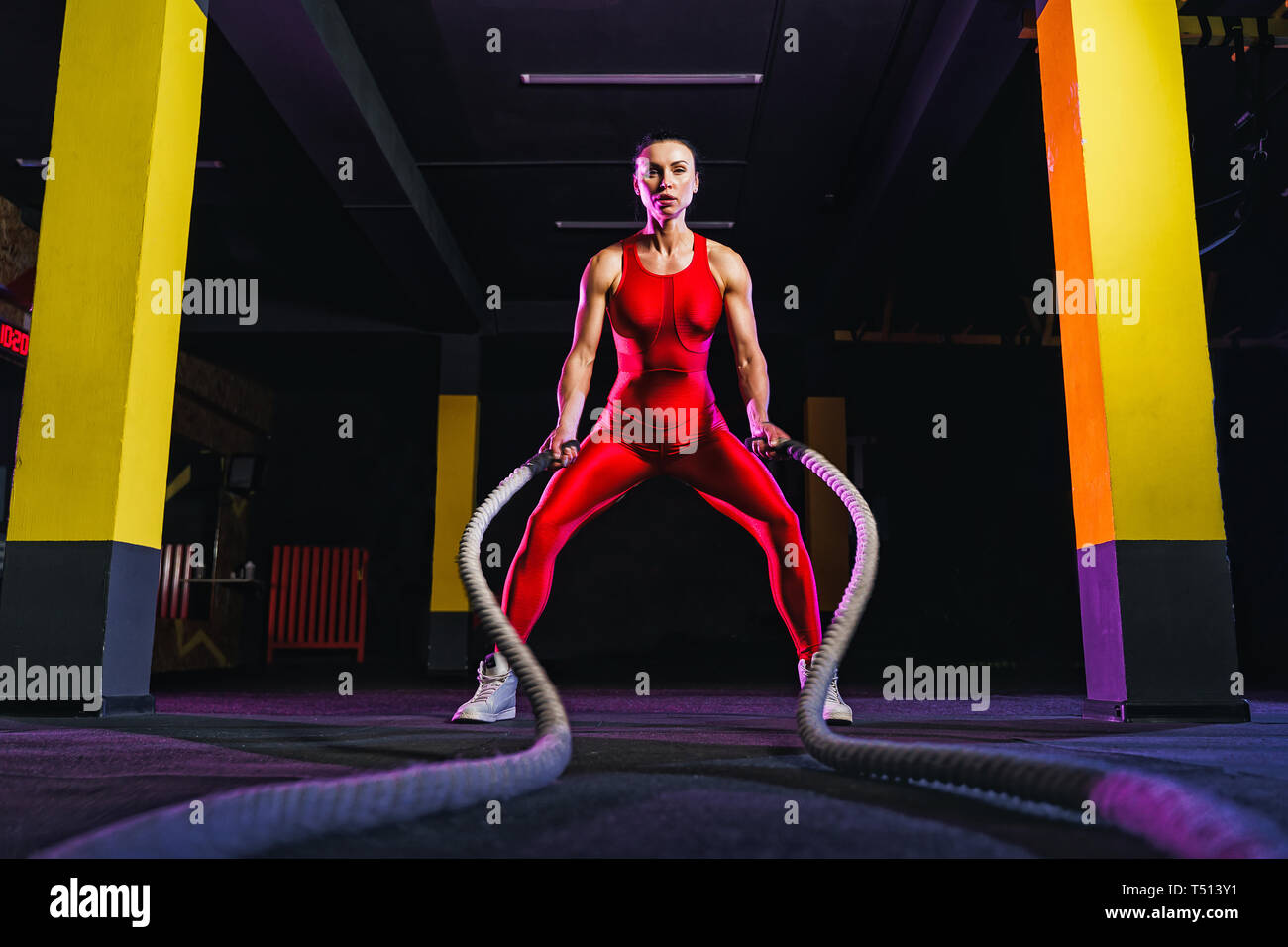 Fitness woman using training ropes for exercise at gym. Athlete working ...