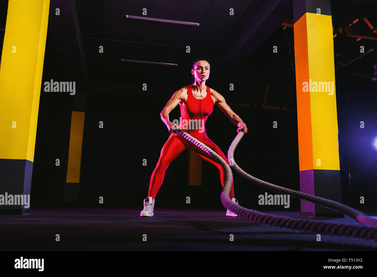 Fitness woman using training ropes for exercise at gym. Athlete working ...