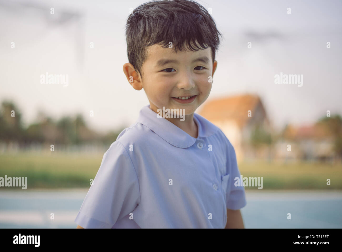 Outdoor portrait of a happy Asian student kid in school uniform smiling ...