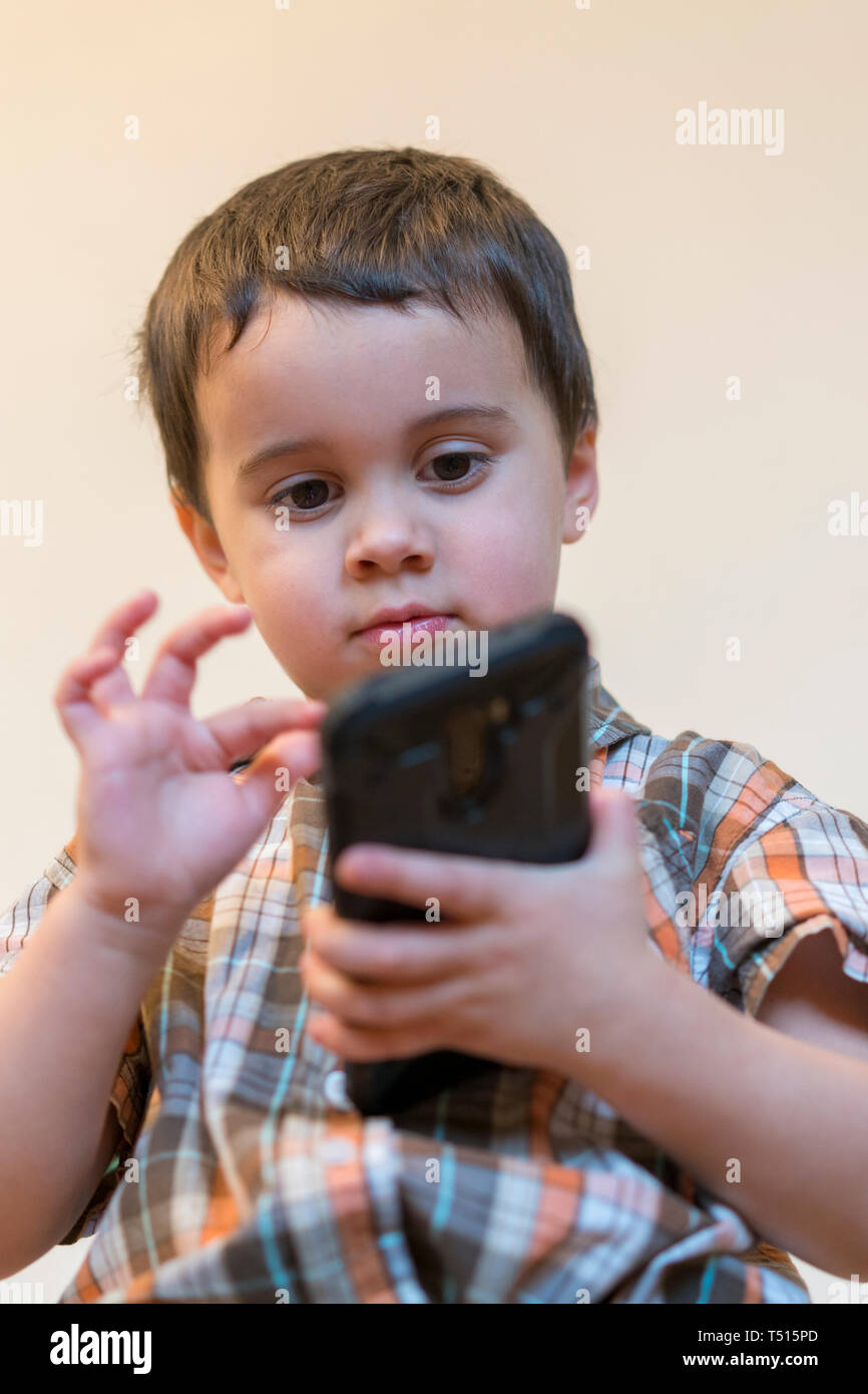 Portrait of a smiling little boy holding mobile phone isolated over ...