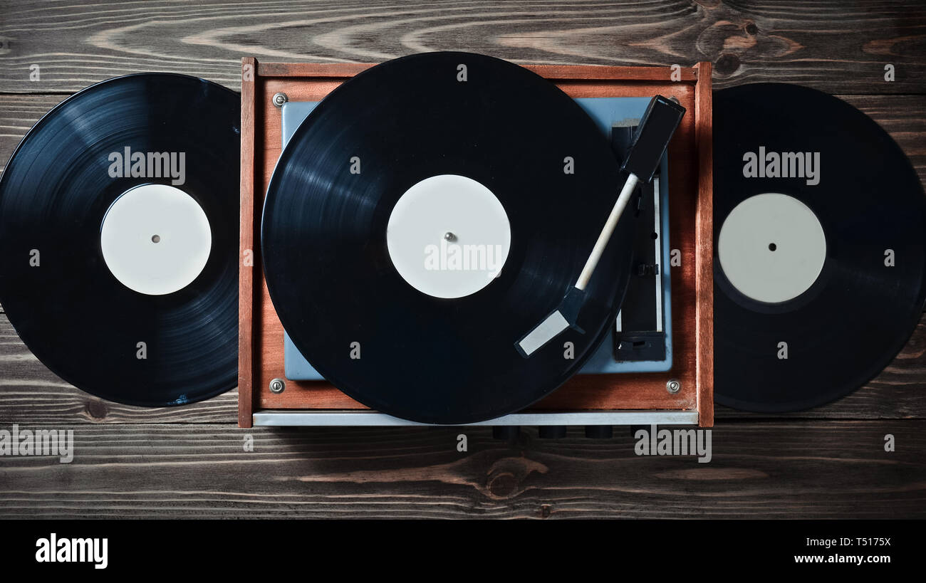 Vinyl player with plates on a wooden table. Entertainment 70s. Listen ...