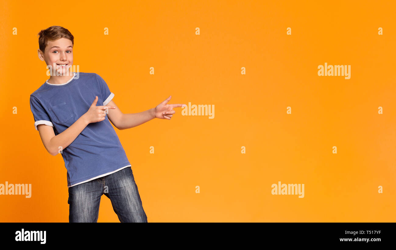 Cheerful teen boy pointing two fingers aside at free space Stock Photo ...