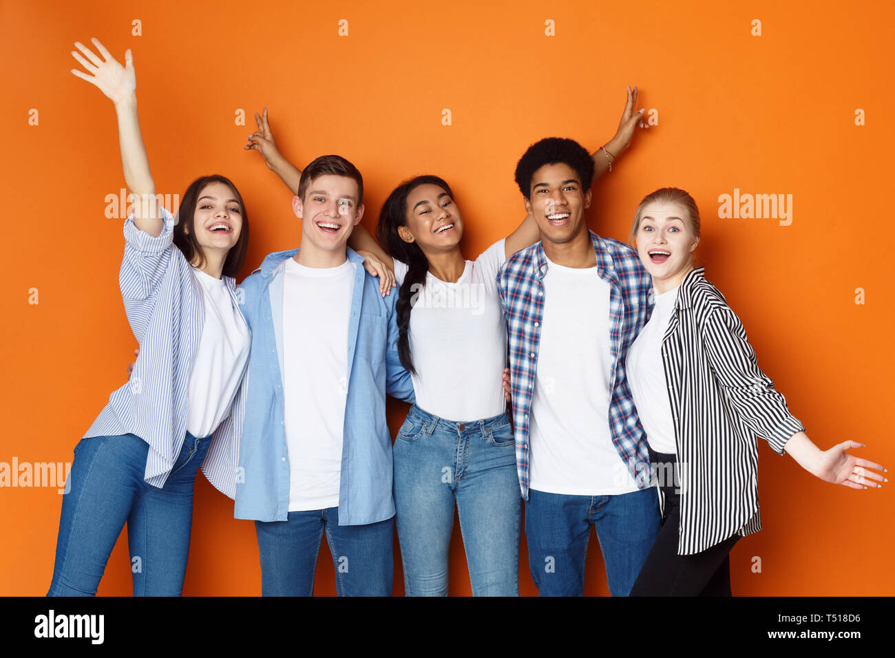 Students having fun over orange studio background Stock Photo - Alamy