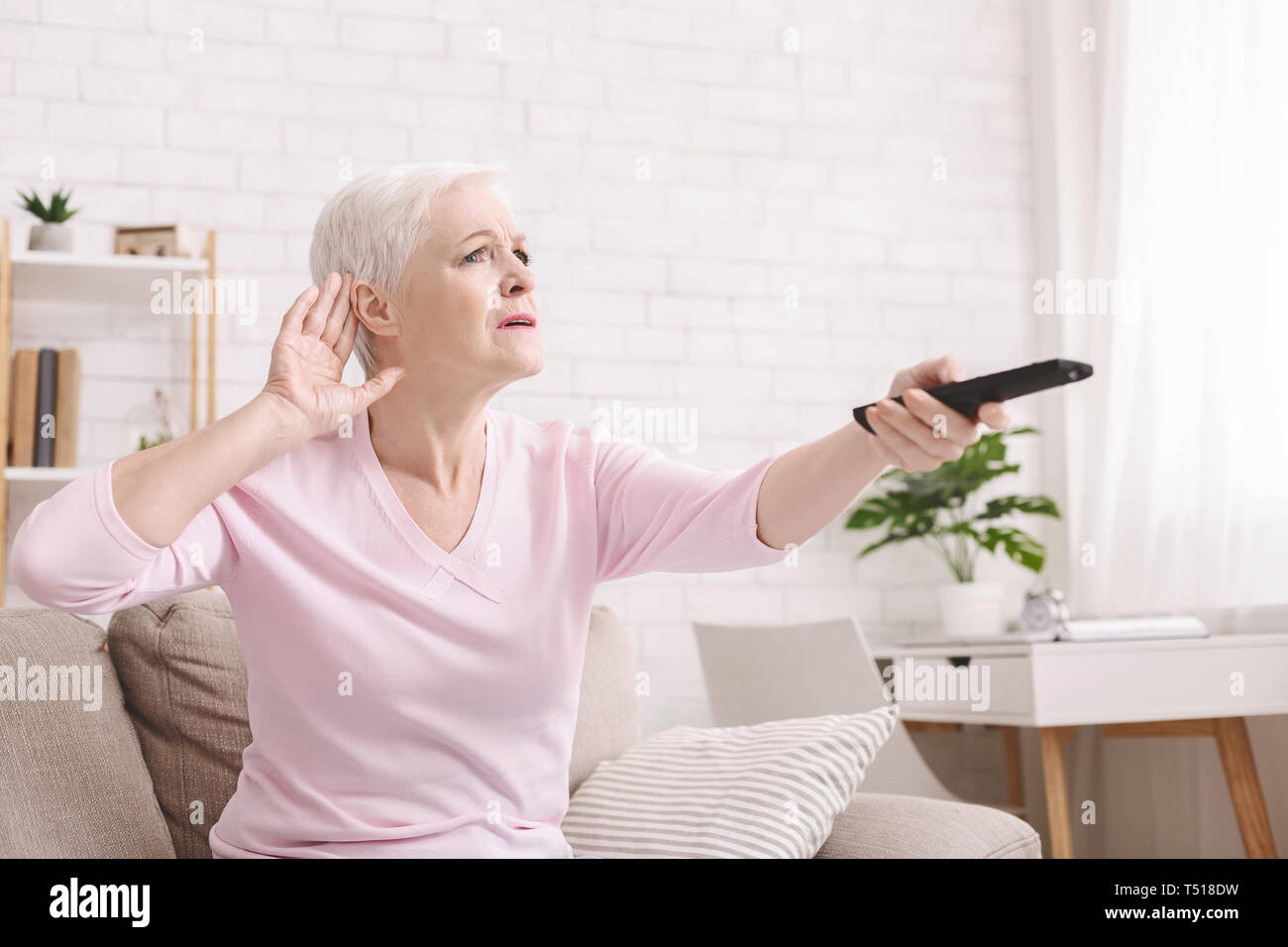 Senior woman cupping her hand behind ear to hear better Stock Photo - Alamy