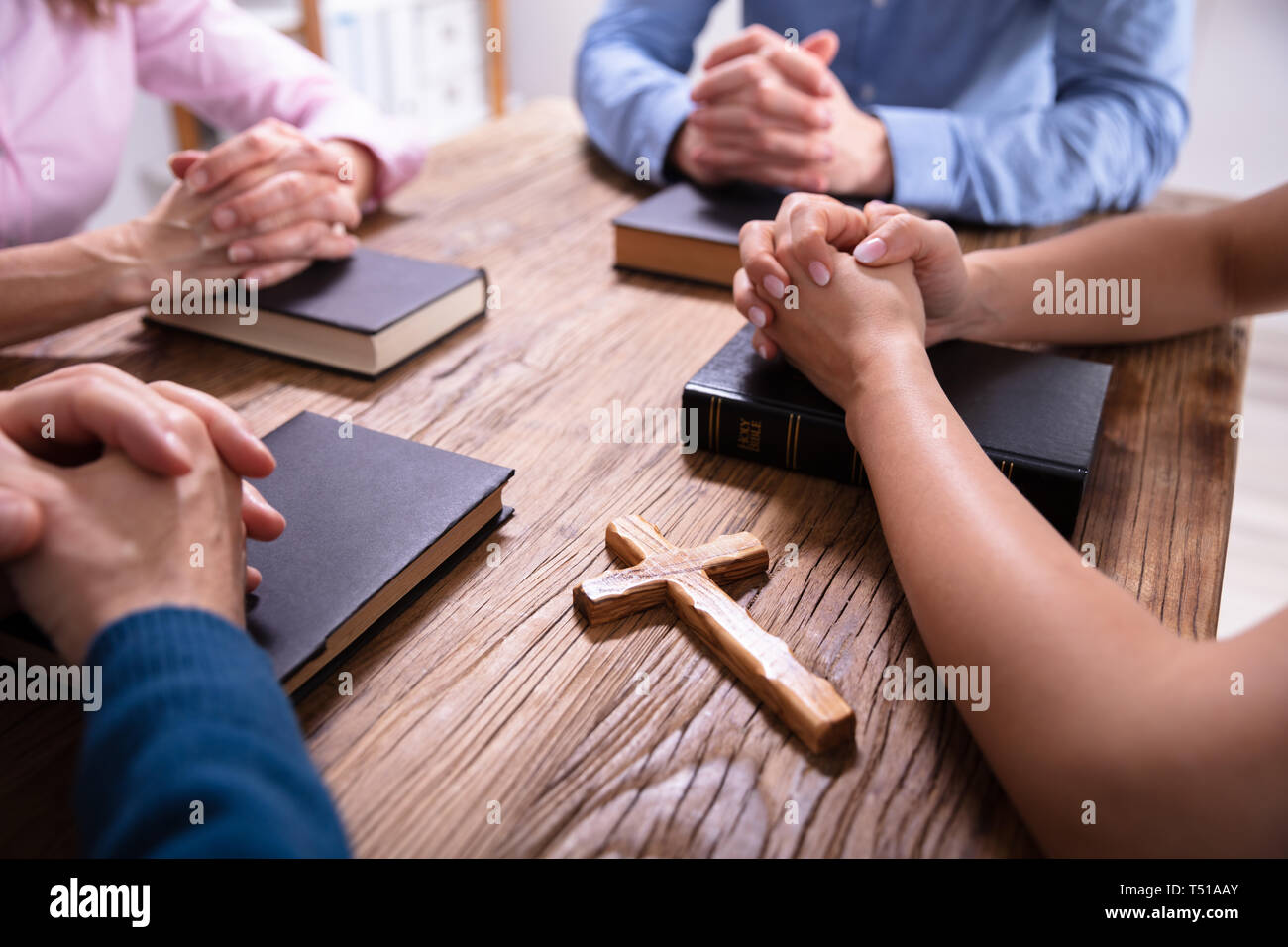 Close-up Of Businesspeople's Praying Hands Over The Bible On Wooden ...