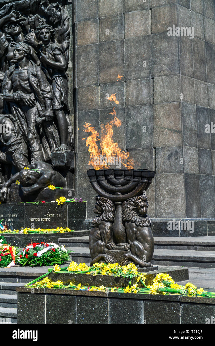 Menorah with burning flame in front of the Warsaw Ghetto Heroes ...