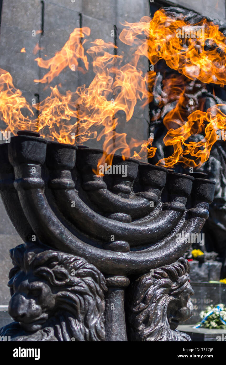 Menorah with burning flame in front of the Warsaw Ghetto Heroes ...