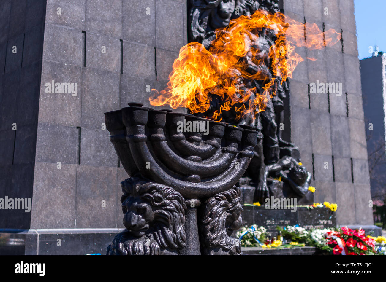 Menorah with burning flame in front of the Warsaw Ghetto Heroes ...