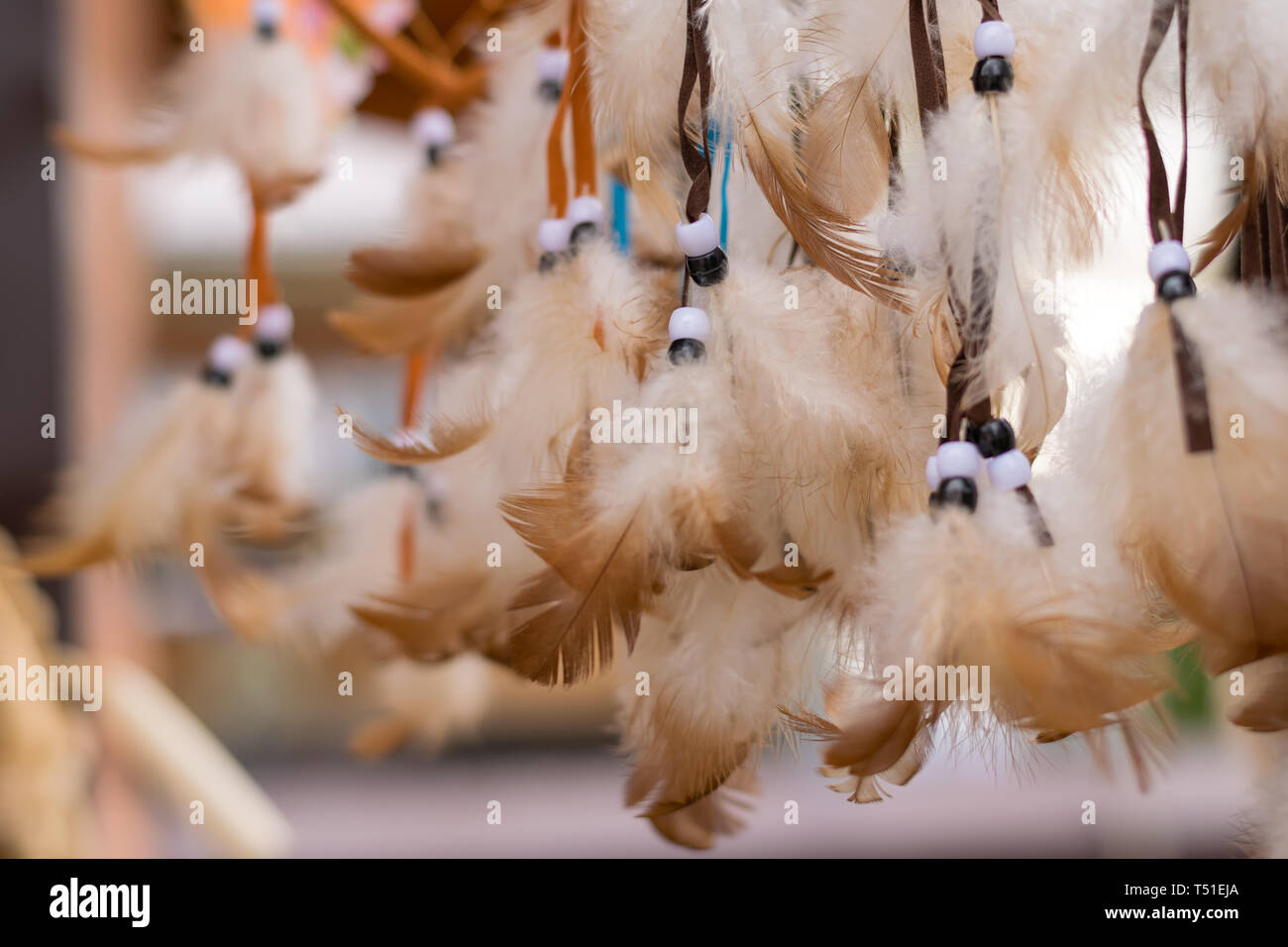 white amulets of feathers with colored ropes hanging on the market for ...