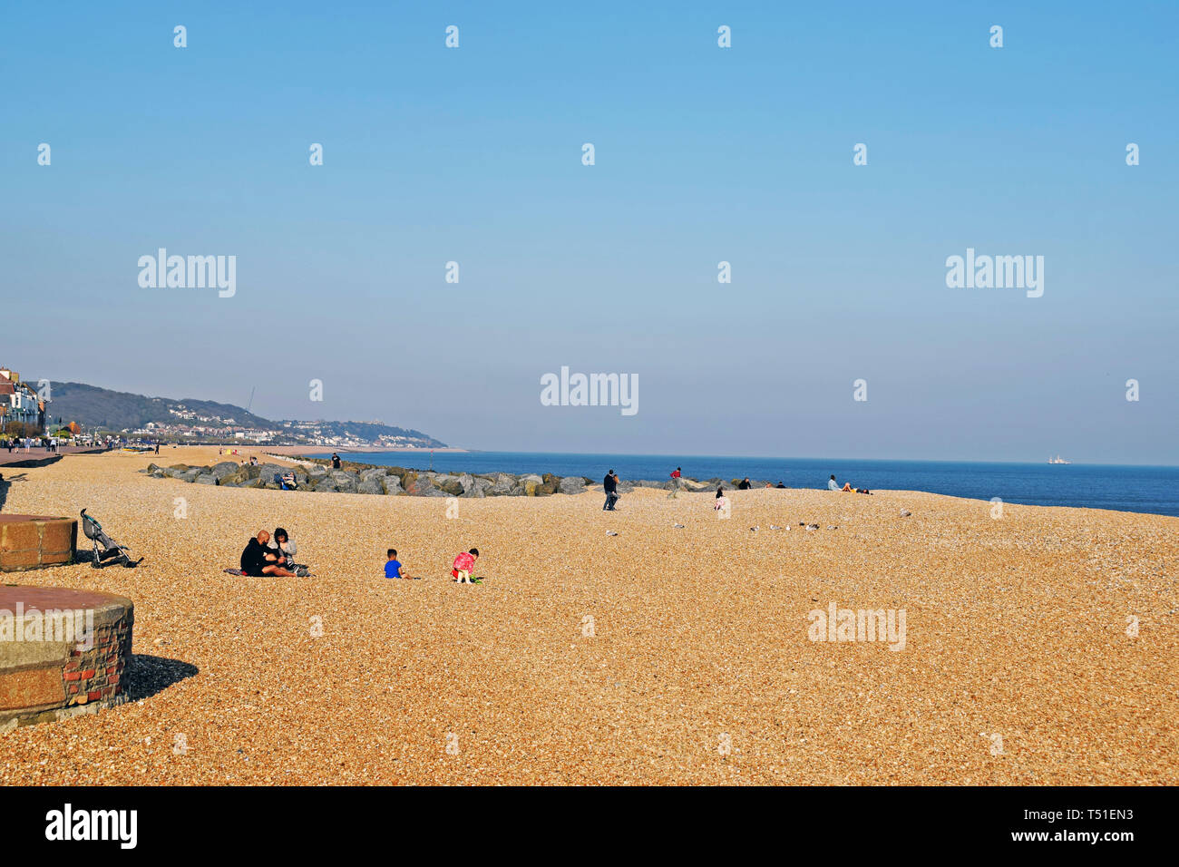 seaside scene in Kent England with people on the pebble beach and blue ...