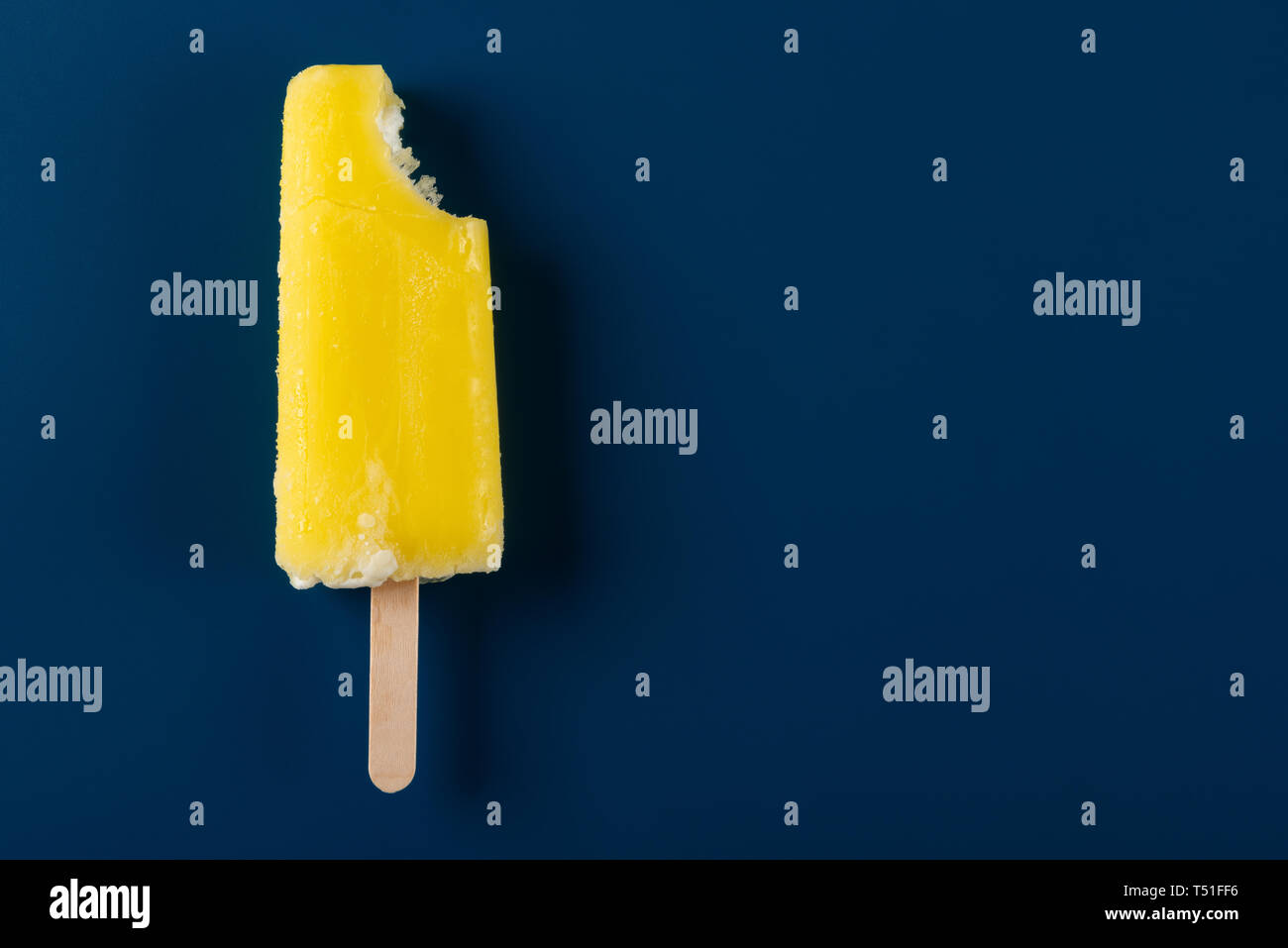 yellow popsicle with a bite on a navy blue background Stock Photo - Alamy