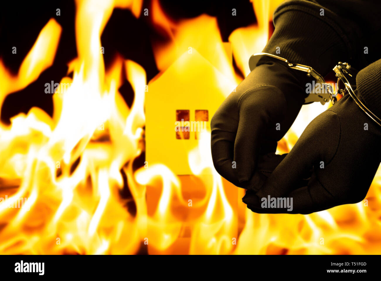 arsonist in handcuffs with a burning house on background Stock Photo ...