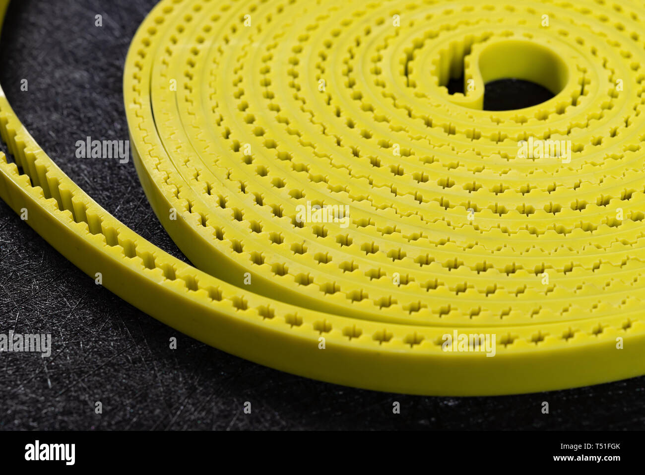 piece of yellow rubber belt gears on a dark background Stock Photo - Alamy