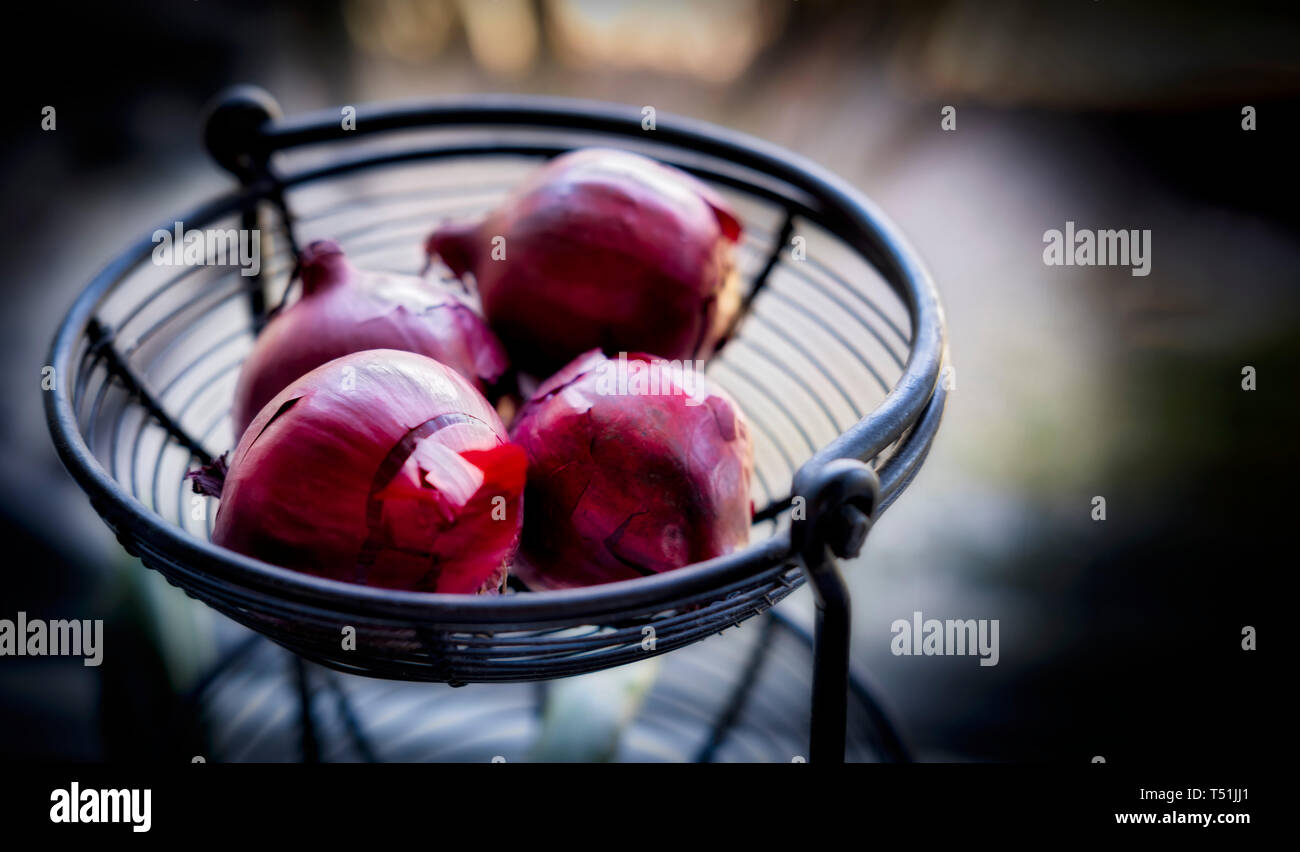 Four red onions in a steel basket Stock Photo - Alamy