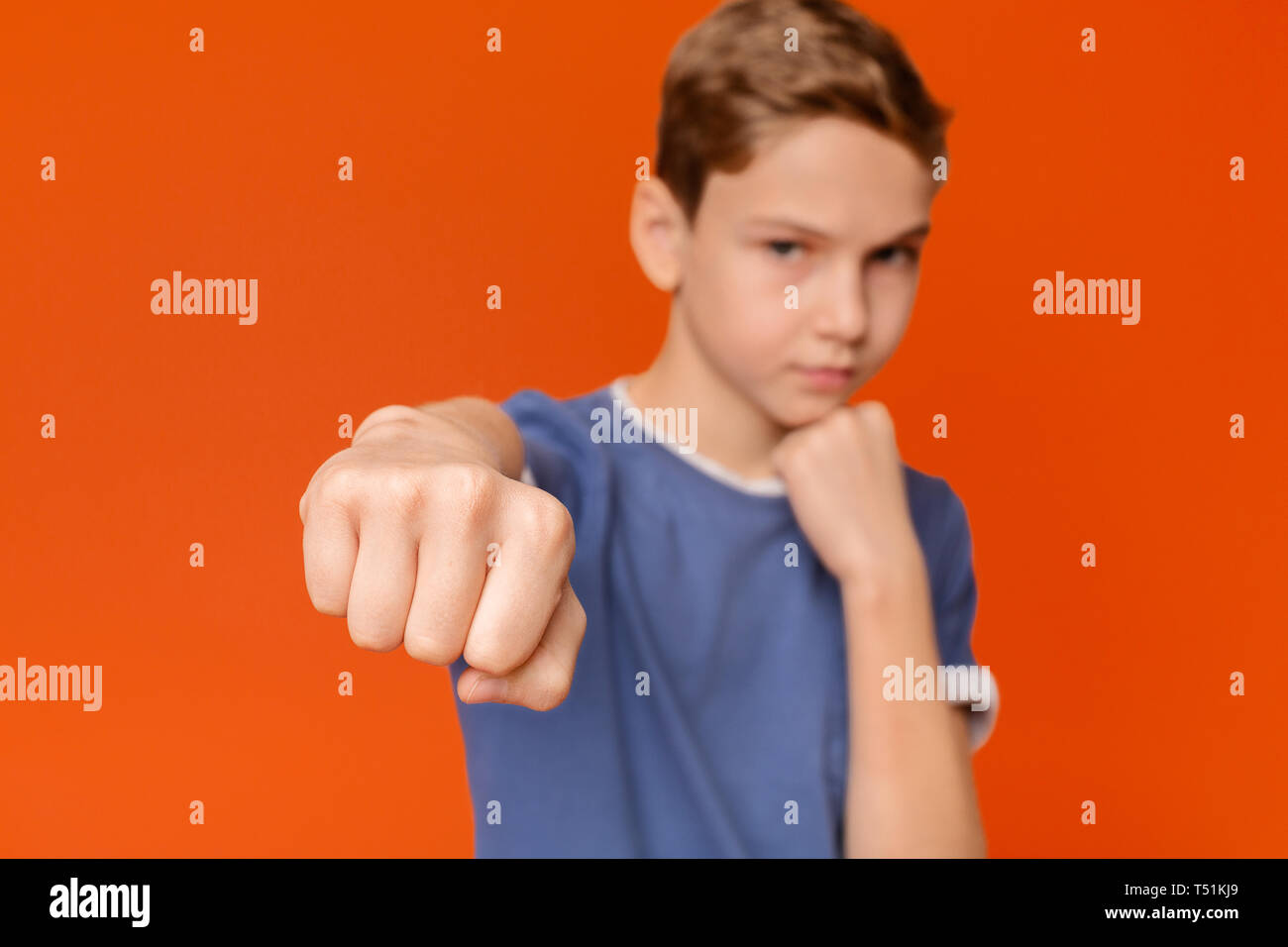 Serious teen boy training box punch, focus on fist, orange studio ...