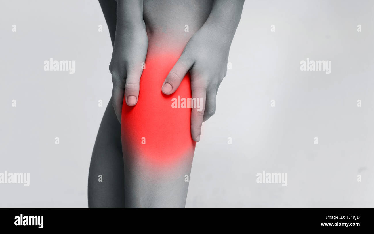 Sport injury. Young woman suffering from pain in leg, massaging ...