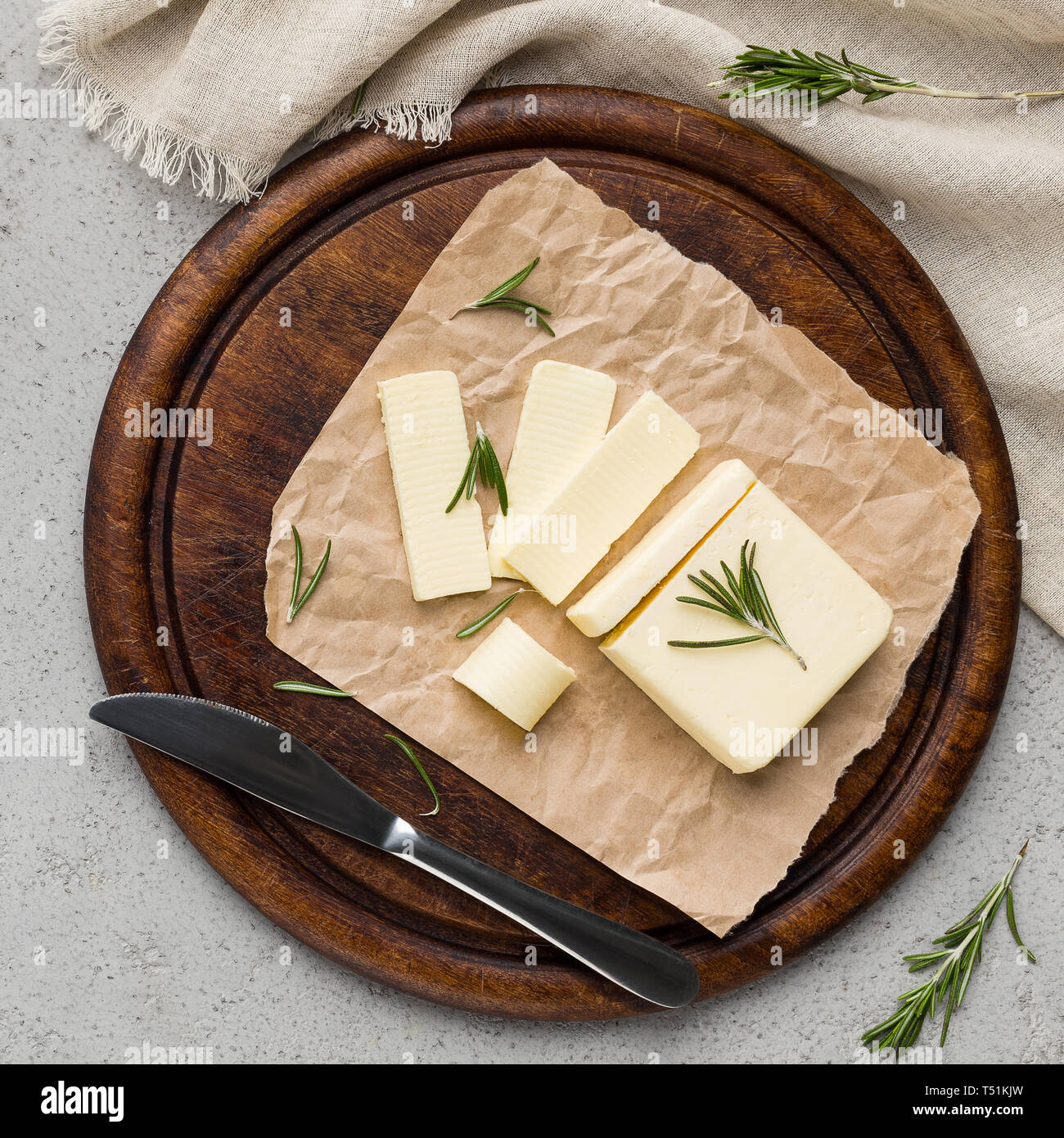 Chopped butter with rosemary on wooden board over concrete background ...