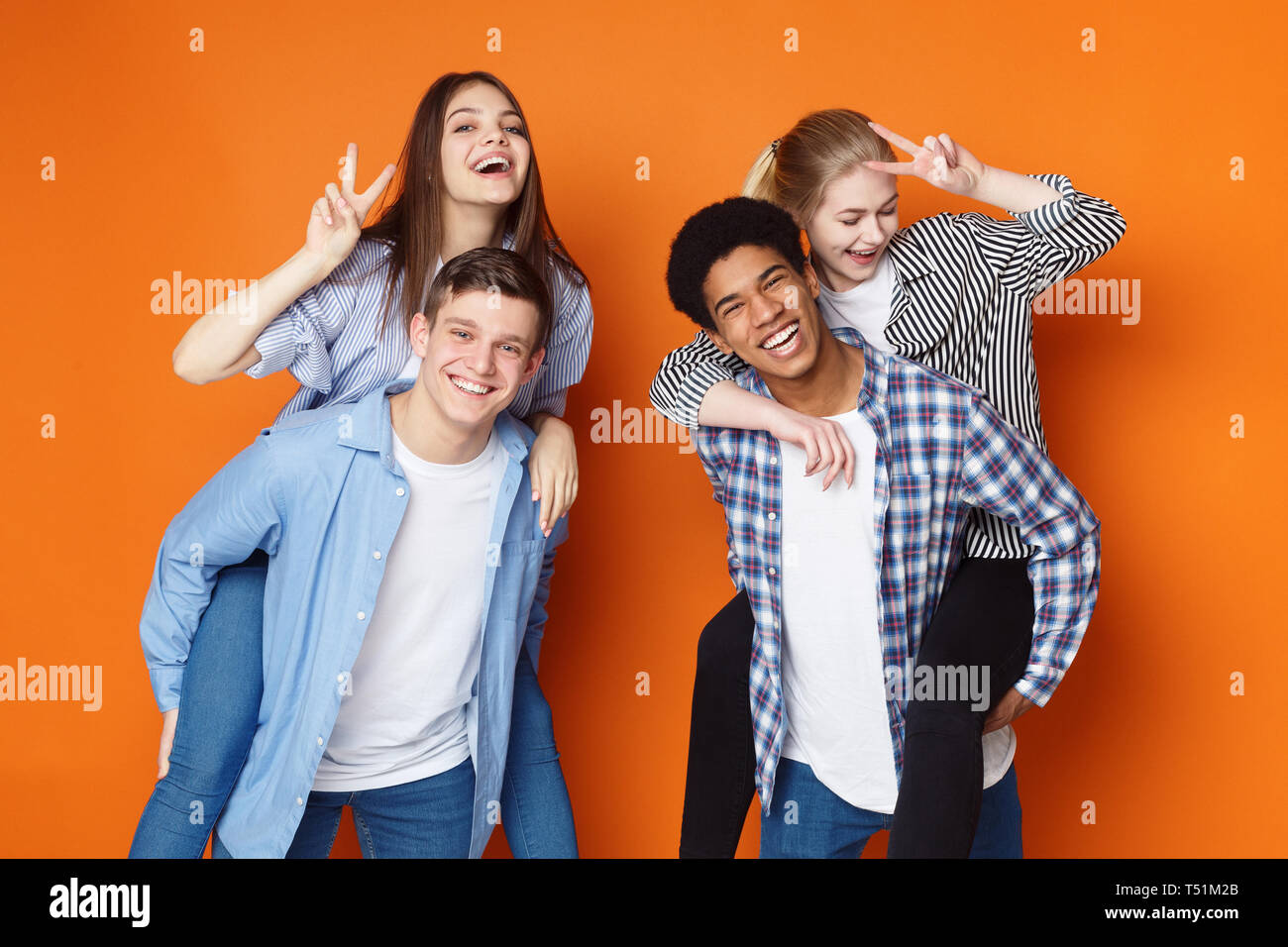 Friends having fun. Guys giving piggyback ride to girls Stock Photo - Alamy