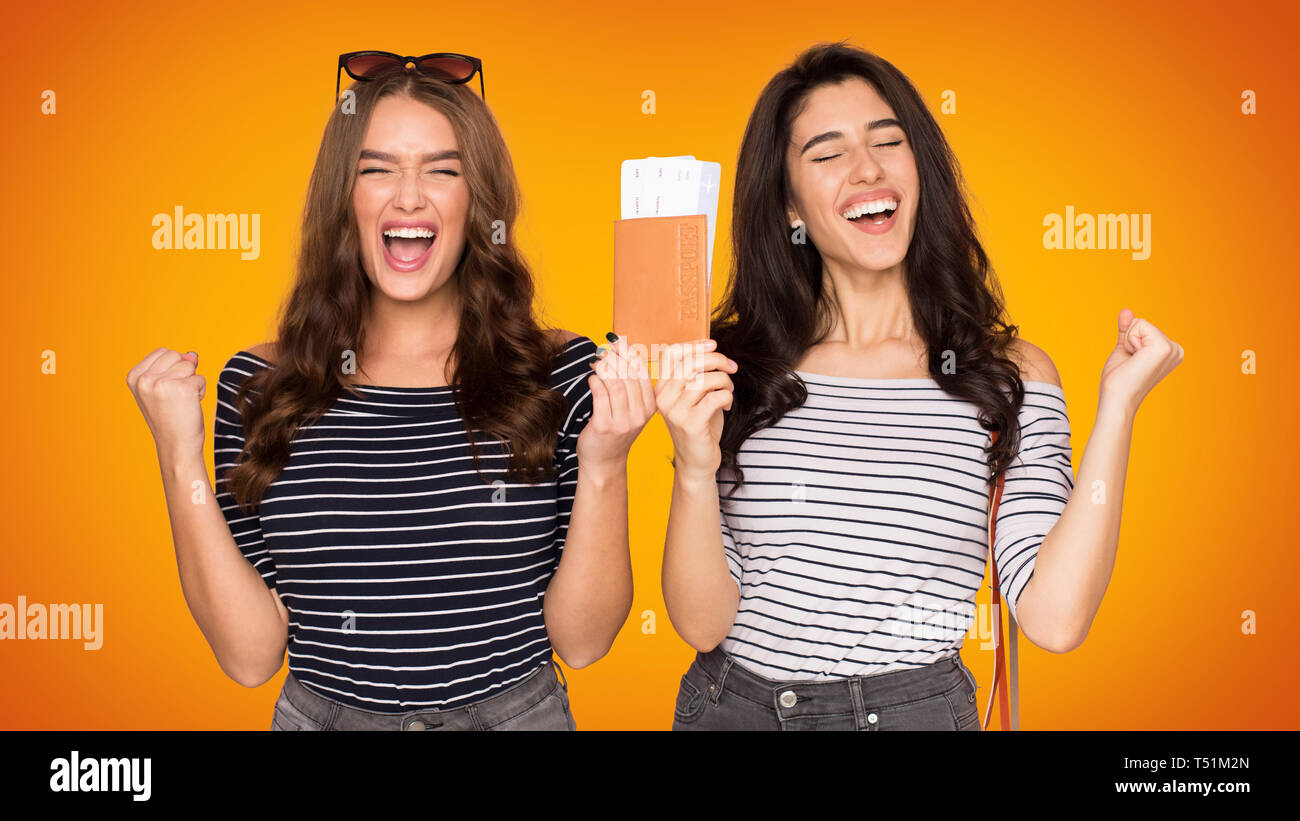 Hurray, vacation! Women holding tickets, orange background Stock Photo ...